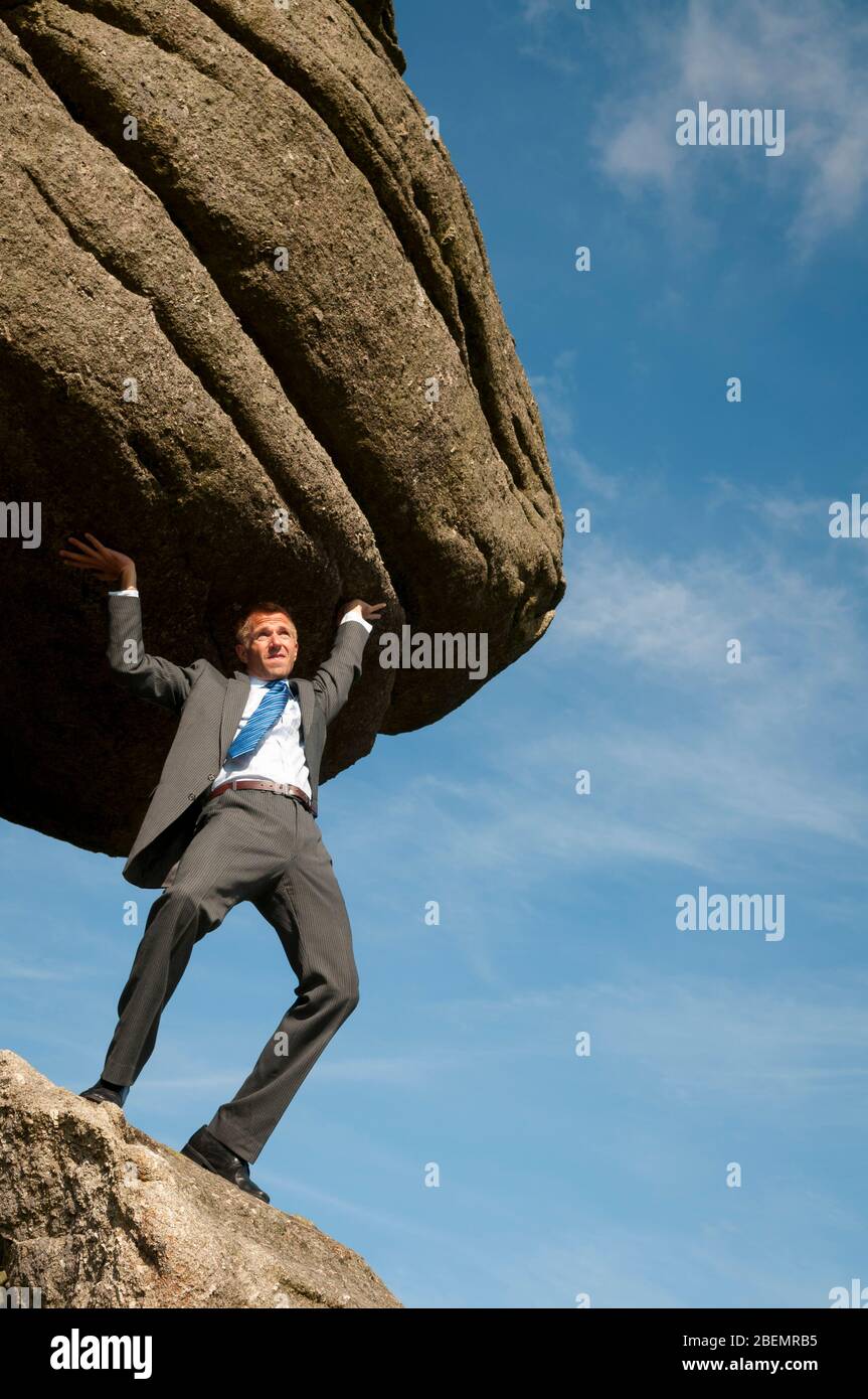 Strong businessman struggling to lift massive boulder into blue sky ...