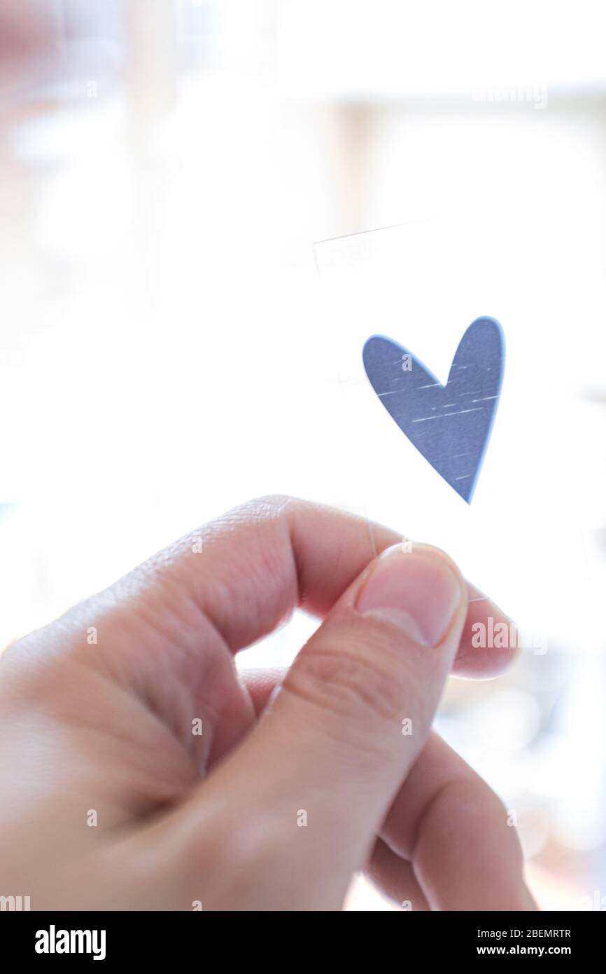Heart shape printed on a transparent glass hold by hand floating in the ...