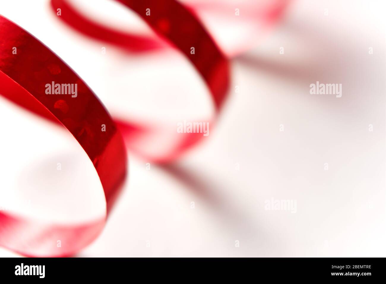 Red curly ribbon on white background. Abstract image of serpentine with ...