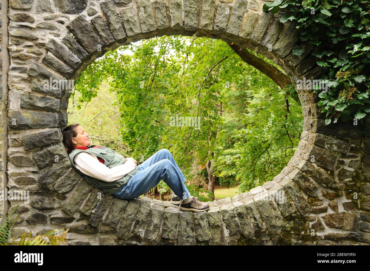 Woman resting on a stone wall feature in the outdoors Stock Photo - Alamy