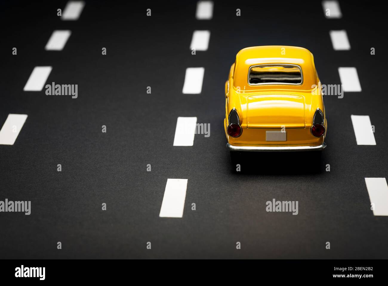Rear view of a Yellow toy car on an asphalt road Stock Photo - Alamy