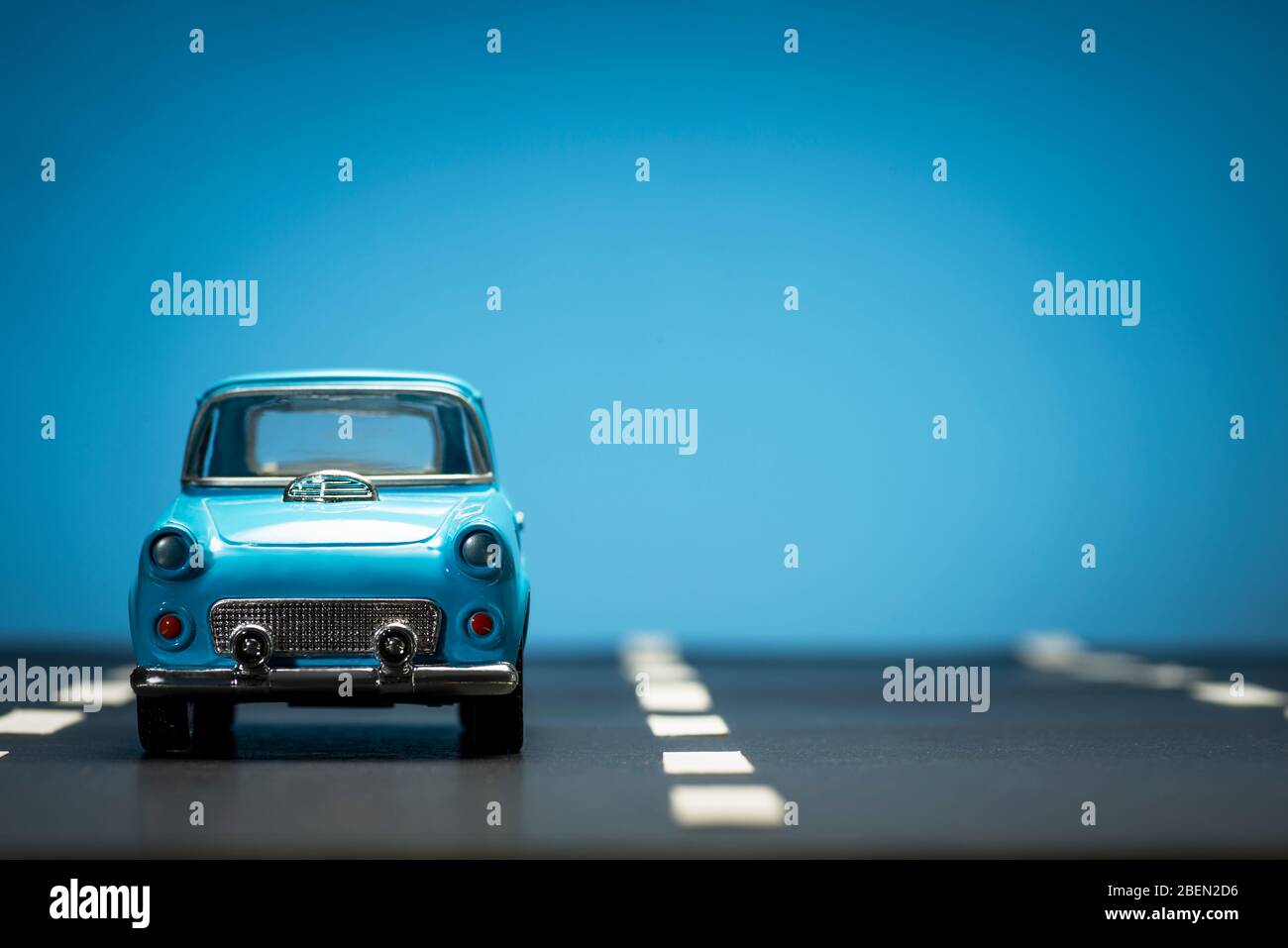 Front view of a blue toy car on on an asphalt road and a blue ...