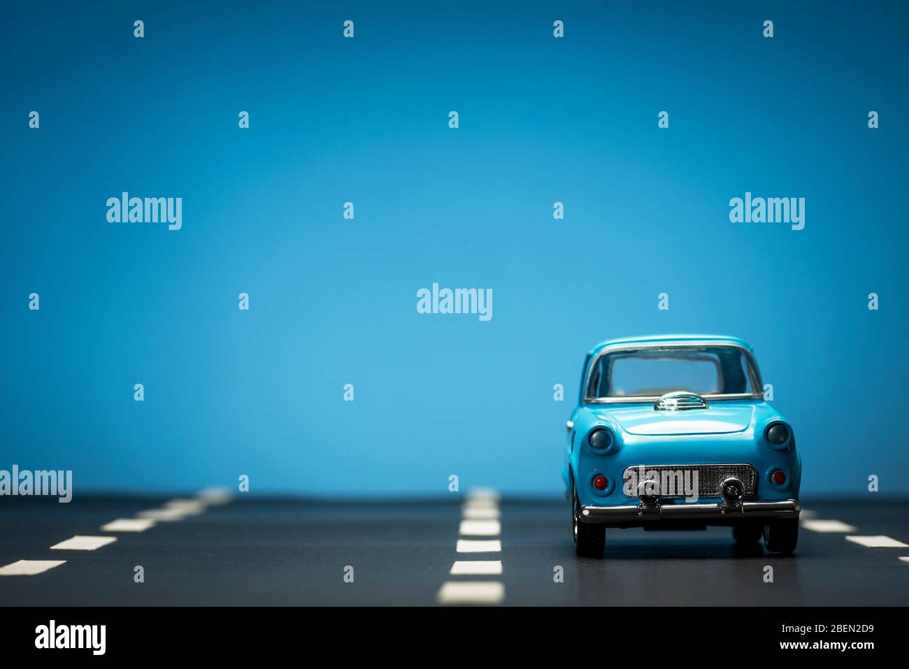 Front view of a blue toy car on on an asphalt road and a blue ...