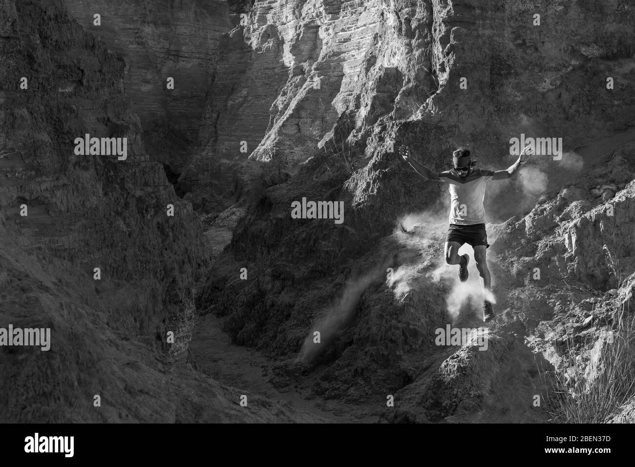 A man trail running down on technical terrain leaving dust on his way ...