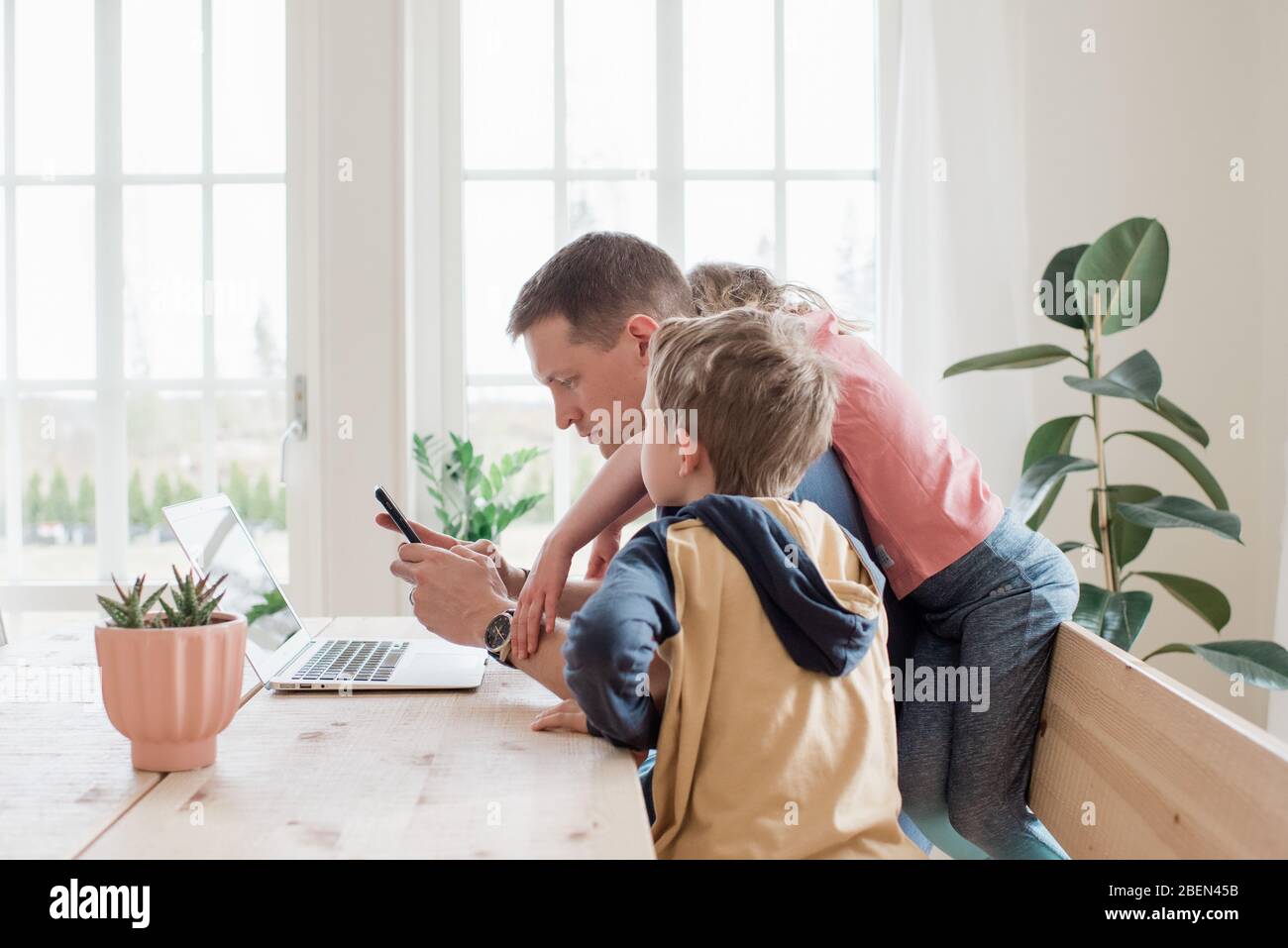 father working from home with his kids climbing over him Stock Photo ...