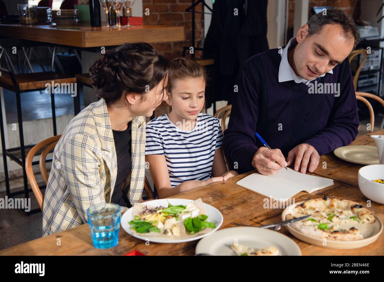 Young parents checking their daughter's homework while sitting at the ...