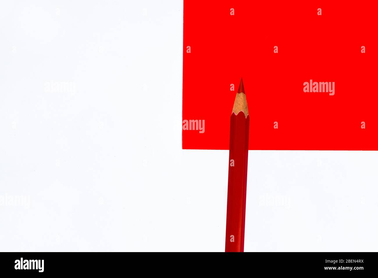 Single wood pencil crayon of red color placed on top of a red white ...