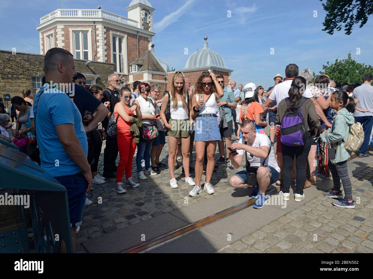 Visitors take photos standing on the Greenwich Meridian line at the ...