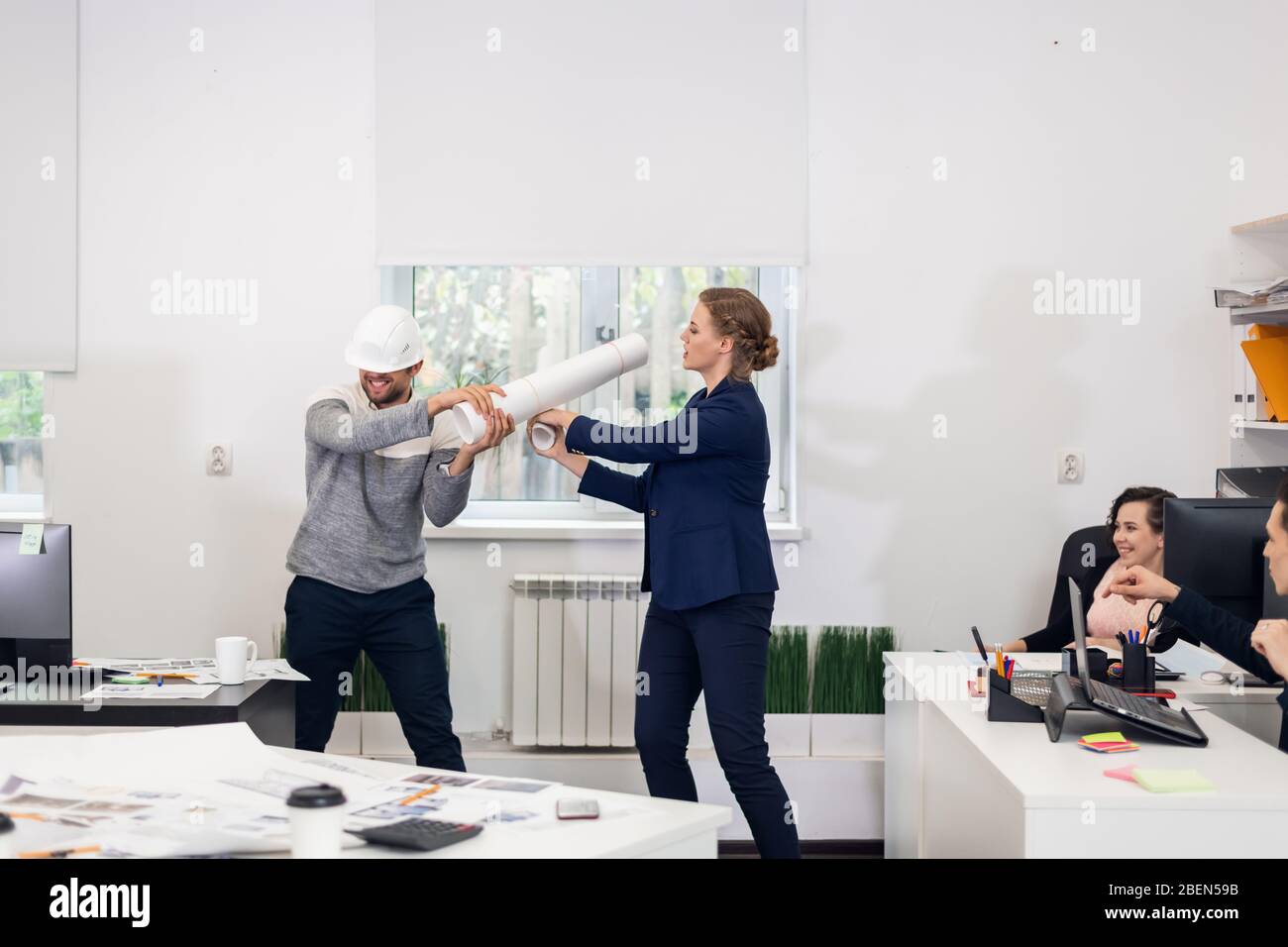 Architects having fun in the office fighting with improvised swords ...