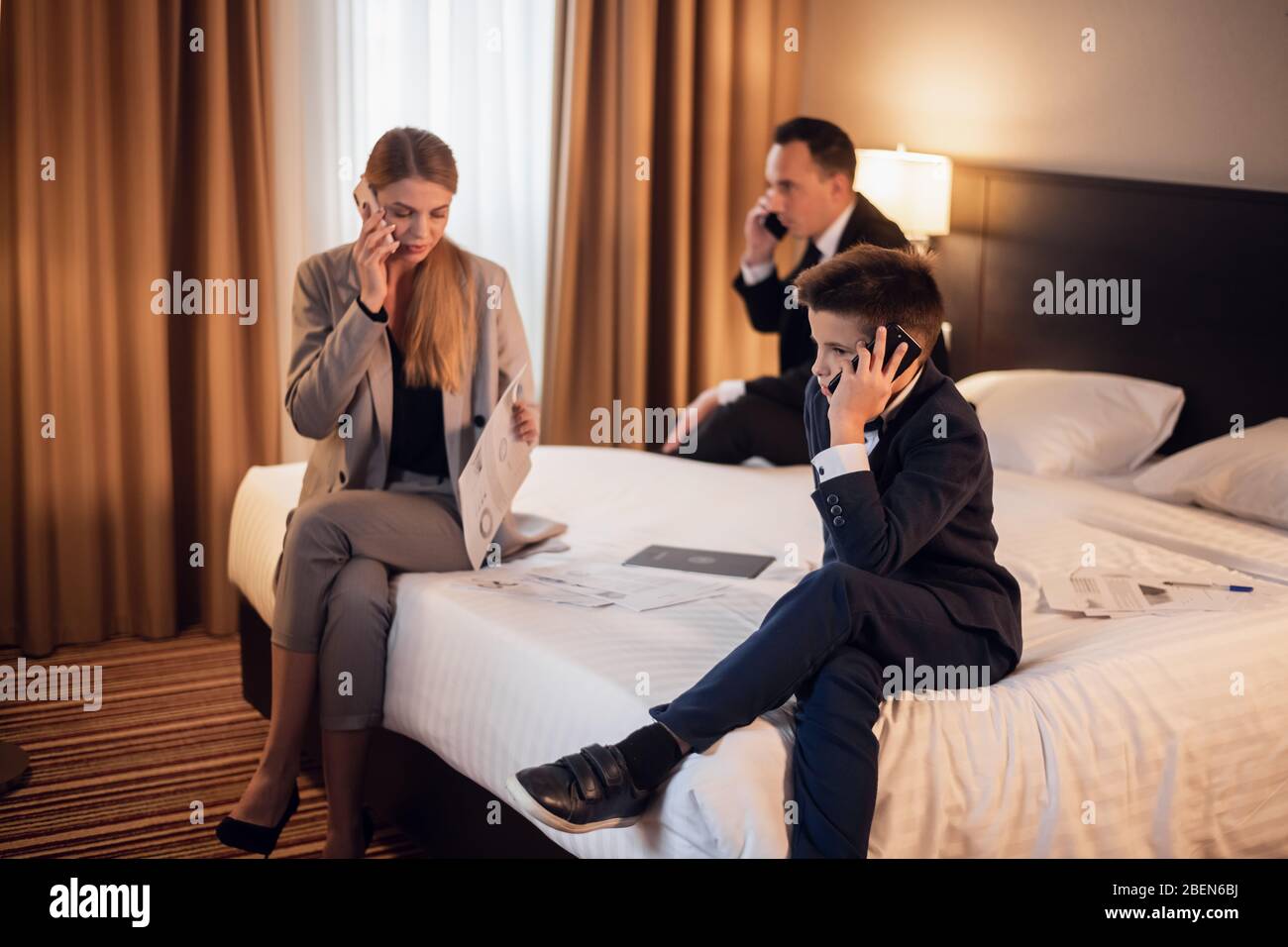 A family of three talking on their phones in a hotel room Stock Photo ...