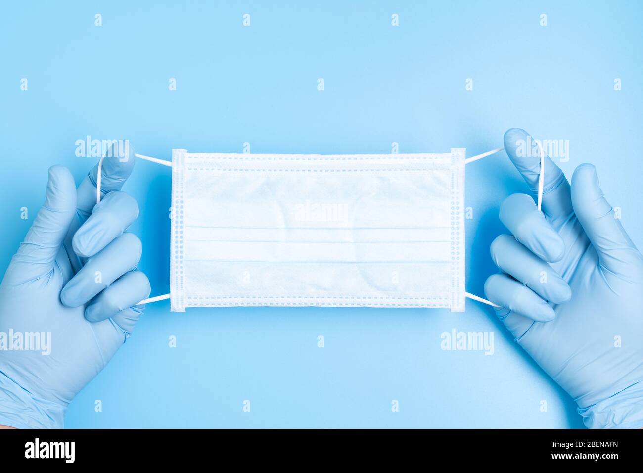 Hand gloves hold face mask in blue background Stock Photo - Alamy