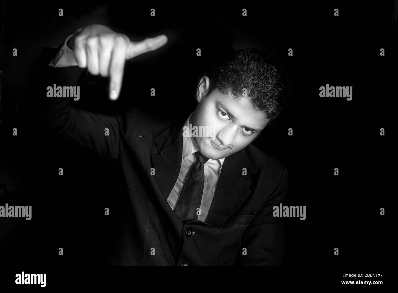 Portrait Shot Of An Arrogant Businessman Posing On A Black Colored Background In A Blue Suit