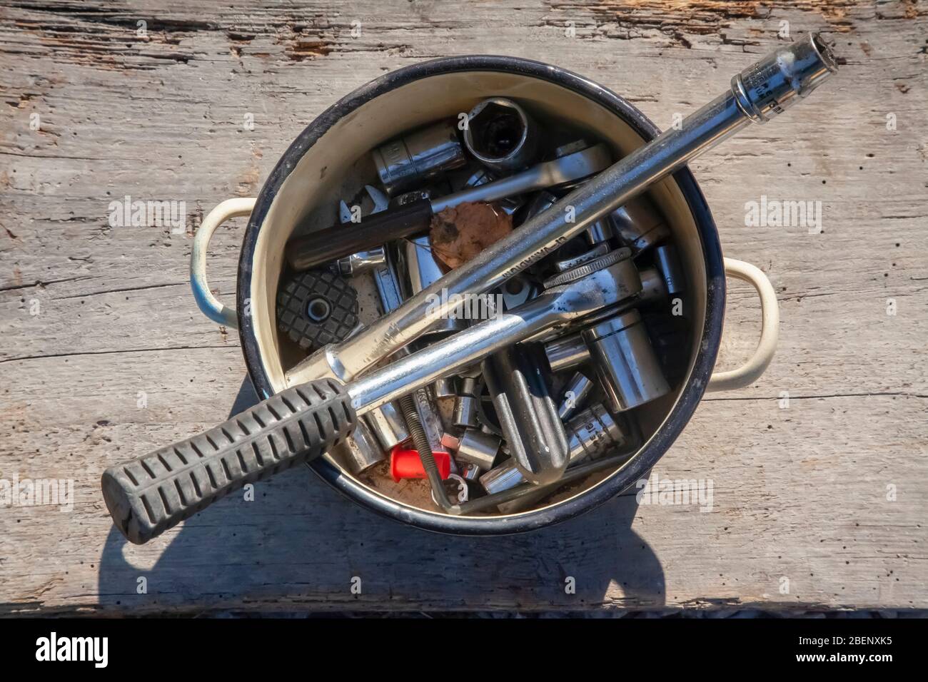 photo of used kitchen pot full of mechanical tools on decayed wooden ...