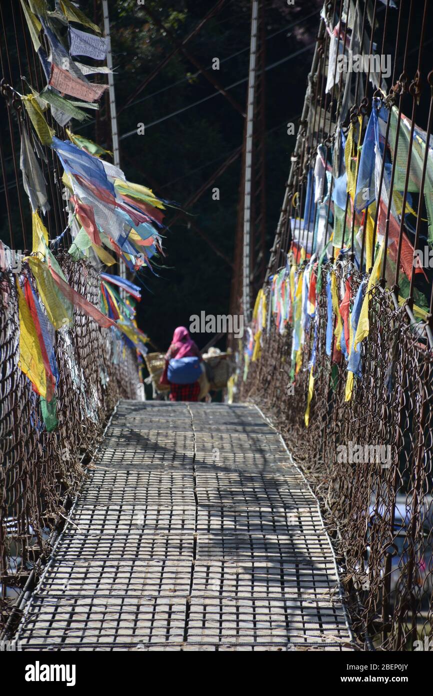 A suspension bridge covered in prayer flags over the The Mo Chhu river ...