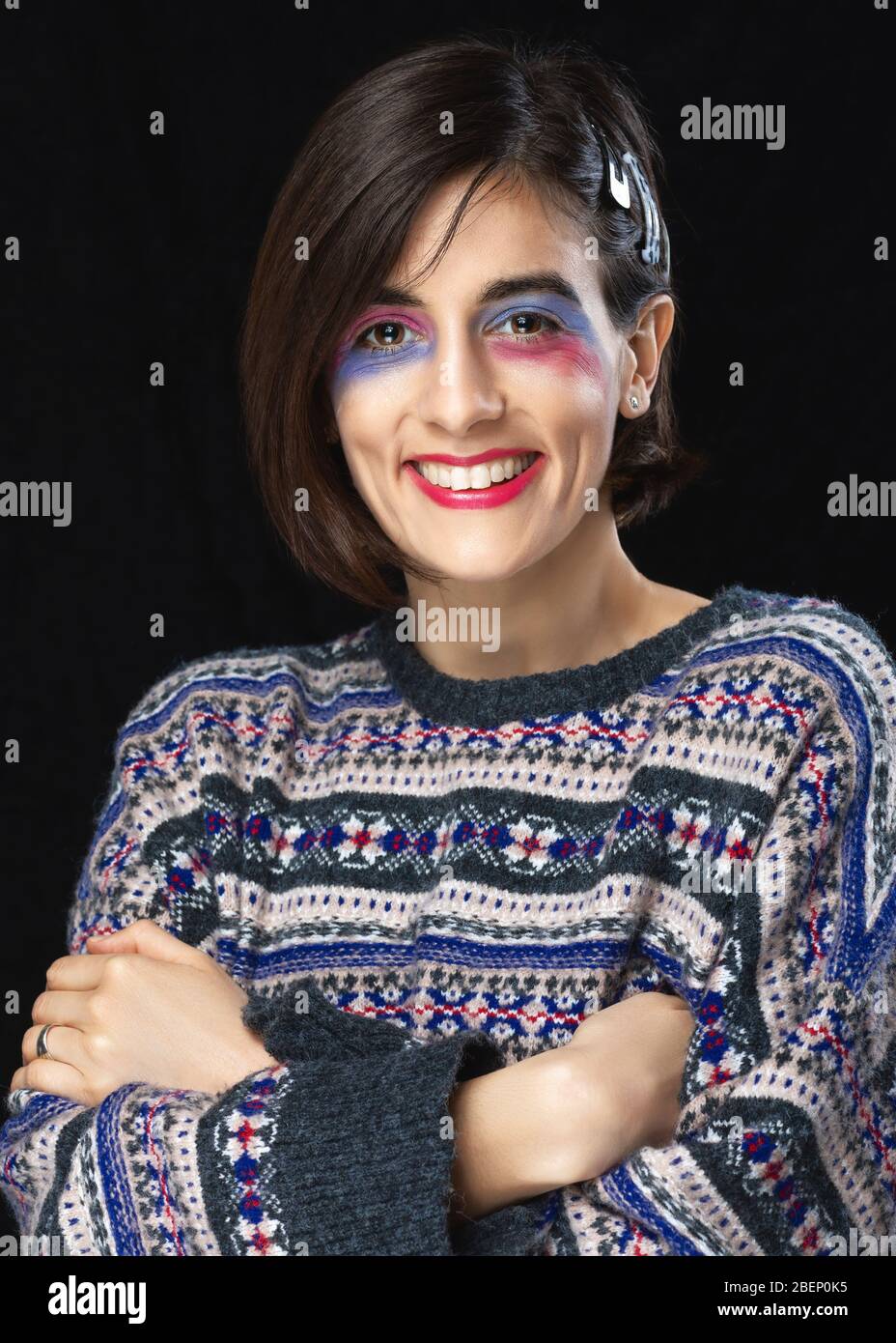 Female with creative make up and colourful sweater posing in studio ...