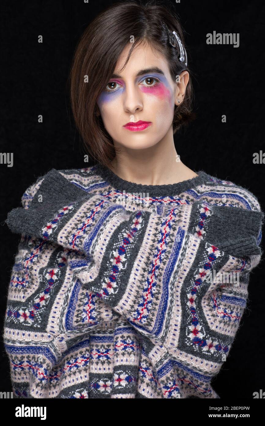 Female with creative make up and colourful sweater posing in studio ...