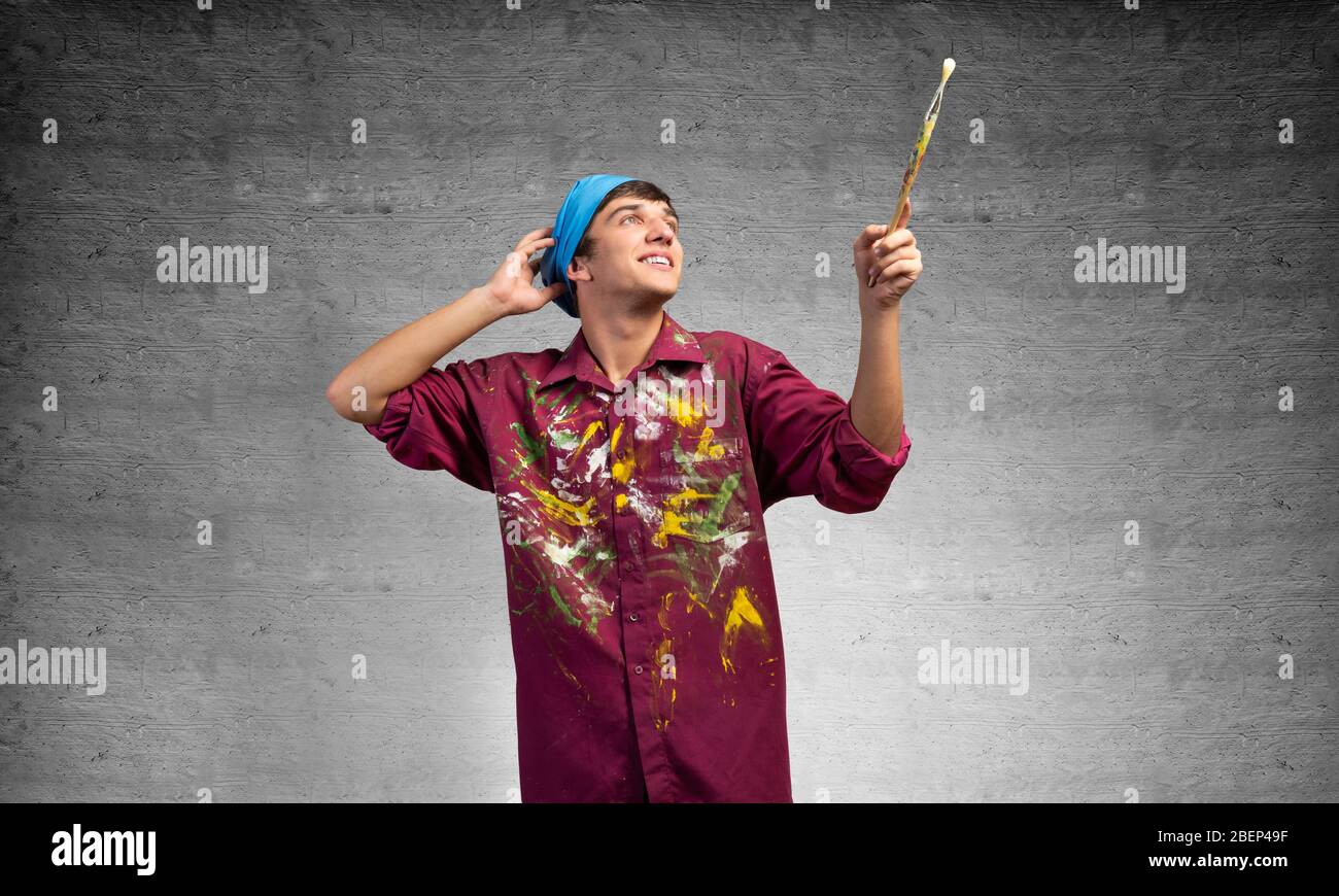 Smiling young painter artist pointing upwards Stock Photo - Alamy