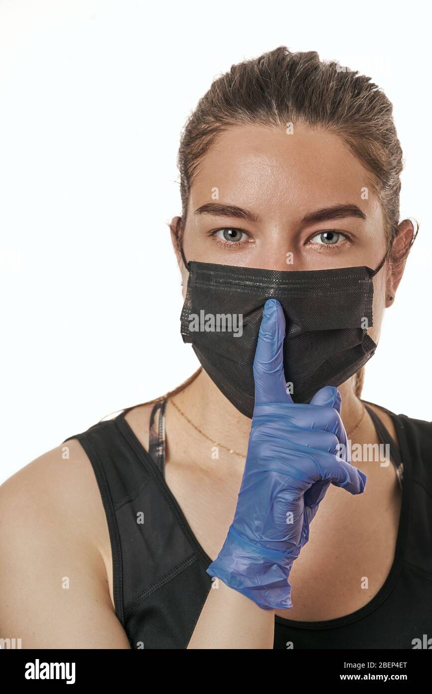 A close-up portrait of a pretty female wearing a surgical mask isolated ...