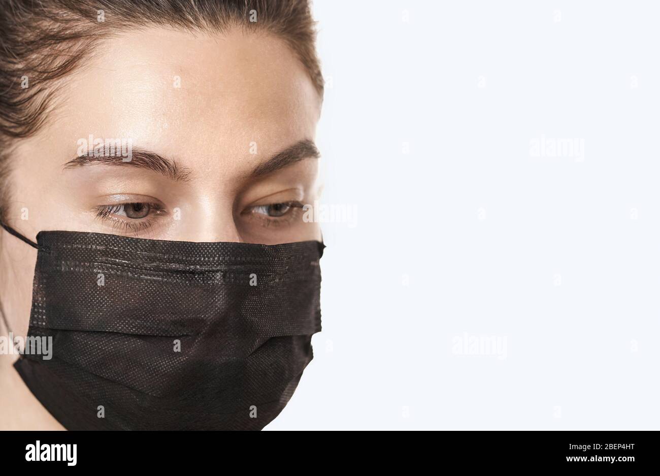 A close-up portrait of a pretty female wearing a surgical mask isolated ...