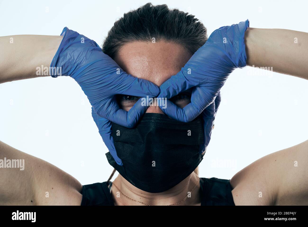 A close-up portrait of a pretty female wearing a surgical mask isolated ...