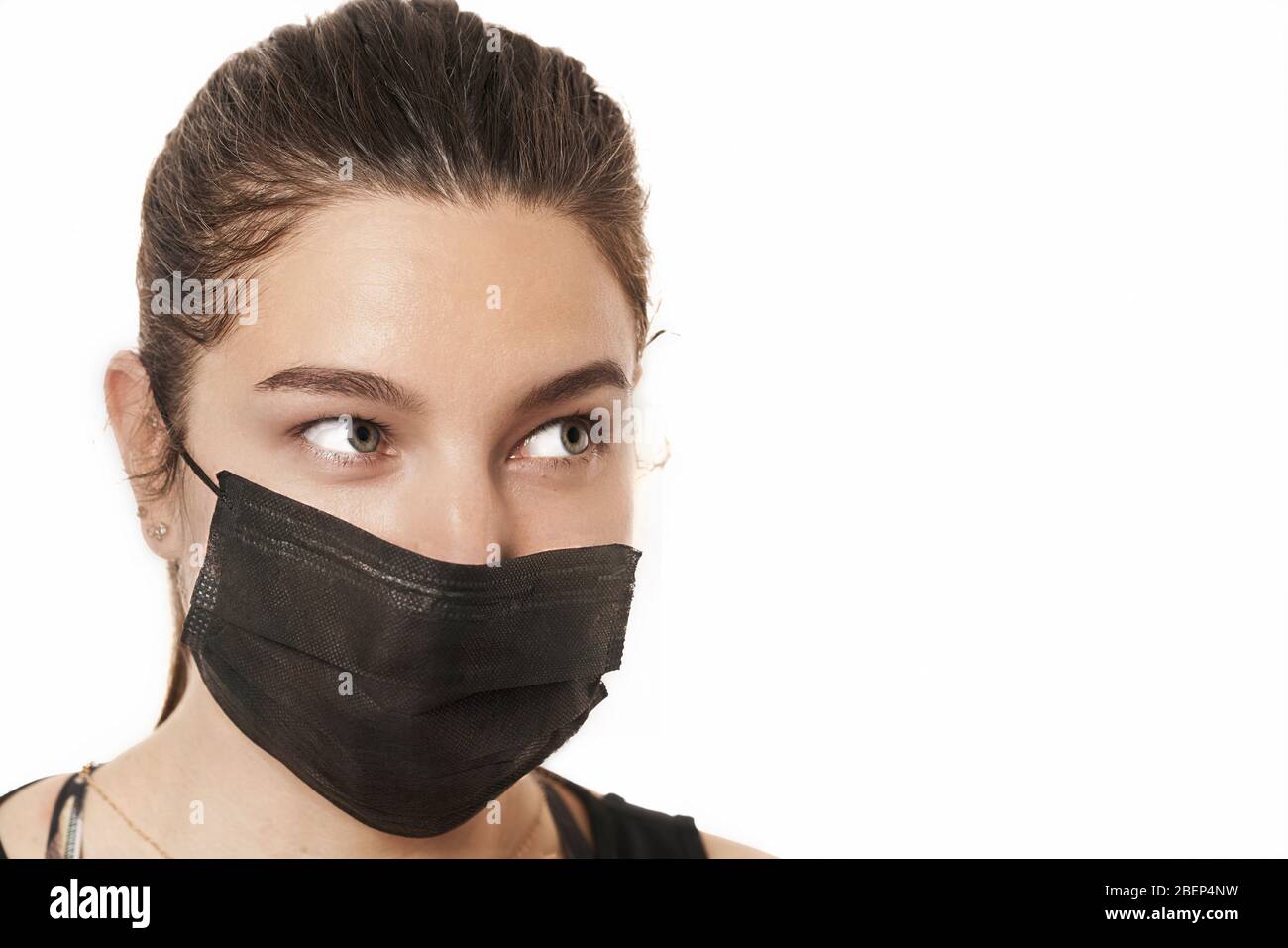 A close-up portrait of a pretty female wearing a surgical mask isolated ...