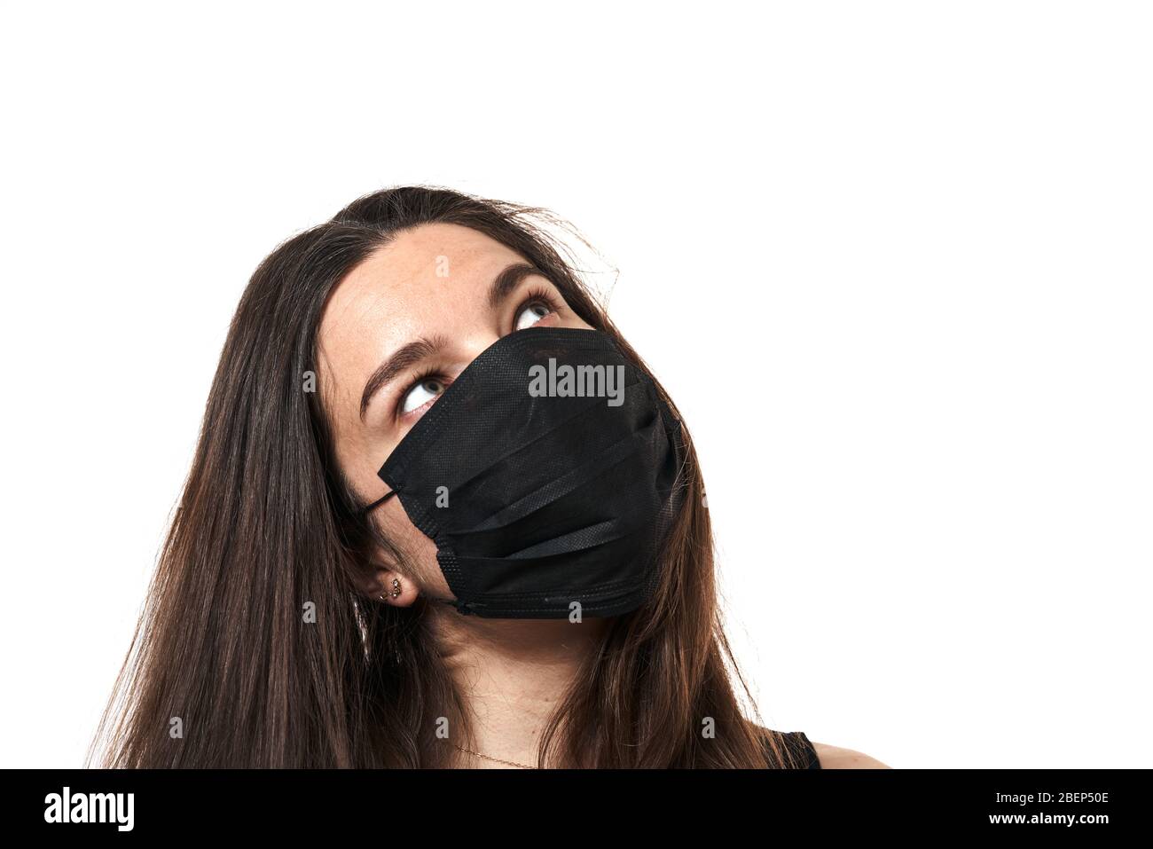 A close-up portrait of a pretty female wearing a surgical mask isolated ...