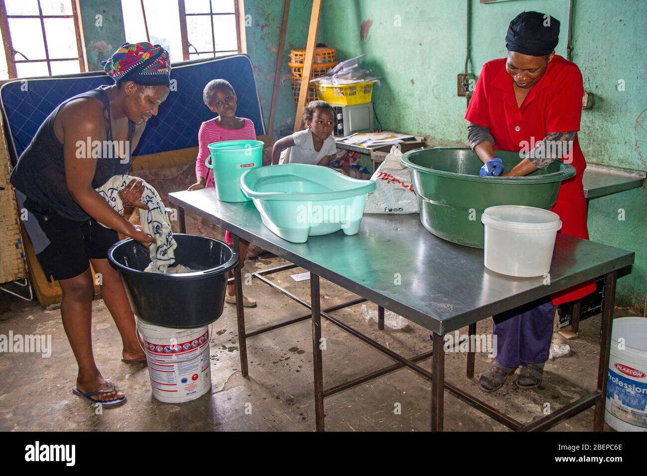 Women wash their clothes in a communal laundry room in the Langa ...