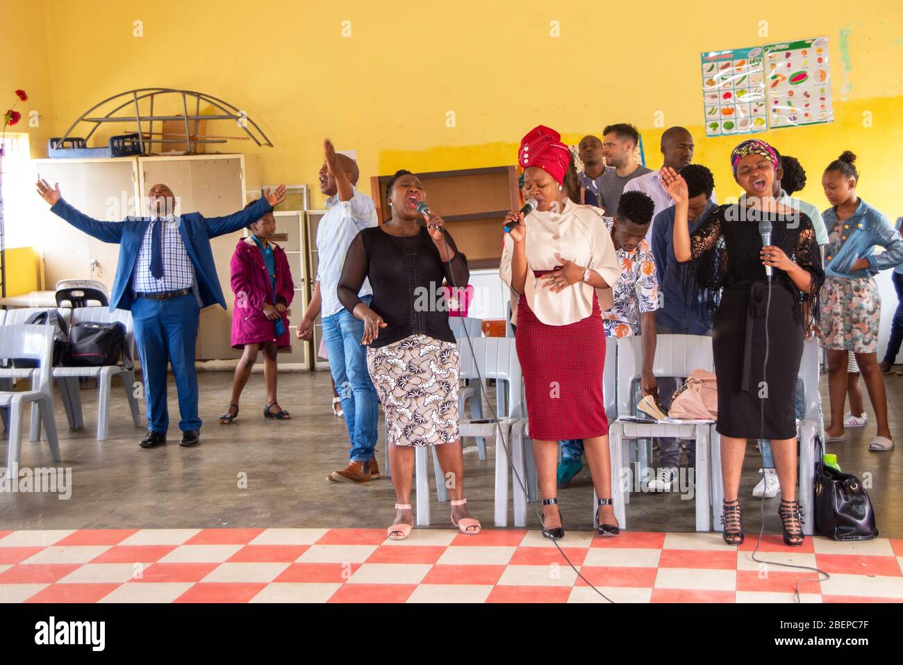 A row of women lead the singing at a community Sunday service in a ...
