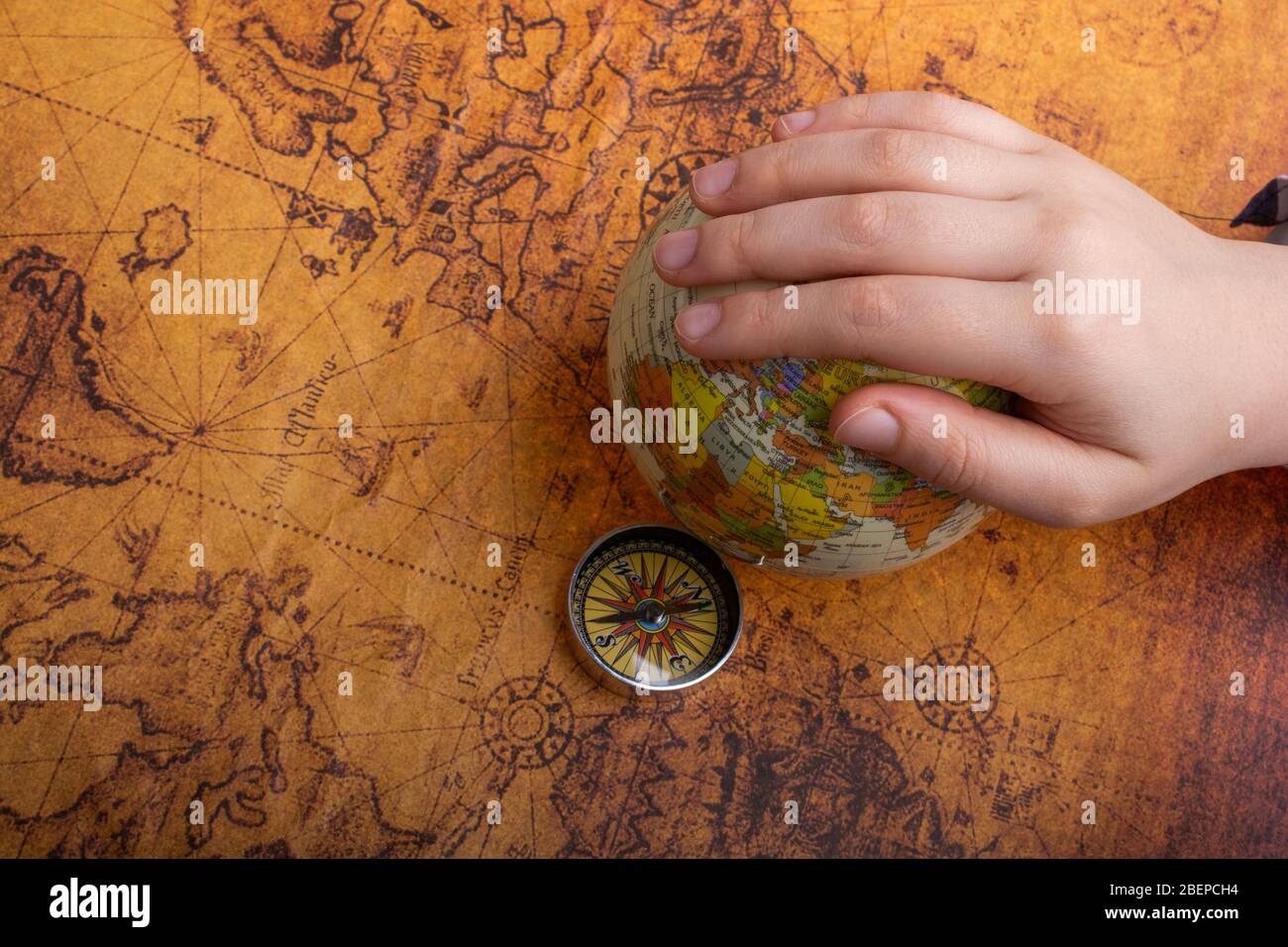 Compass on map beside a globe under hand Stock Photo - Alamy