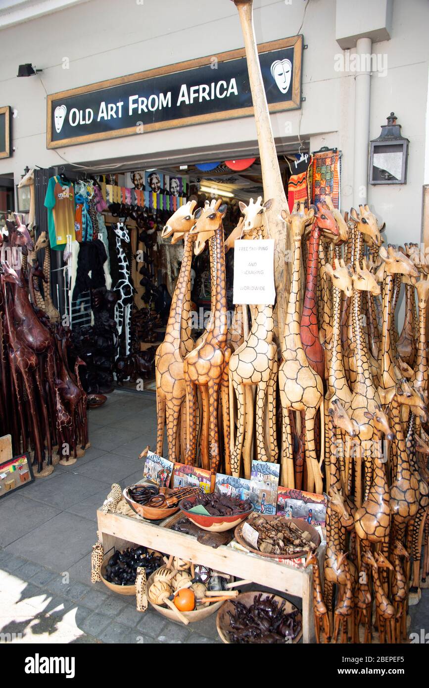 A shop sells wood carvings of African animals. Giraffes line the ...