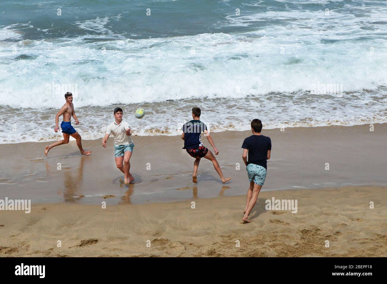Four fit white South African teenagers play rugby on the beach in ...