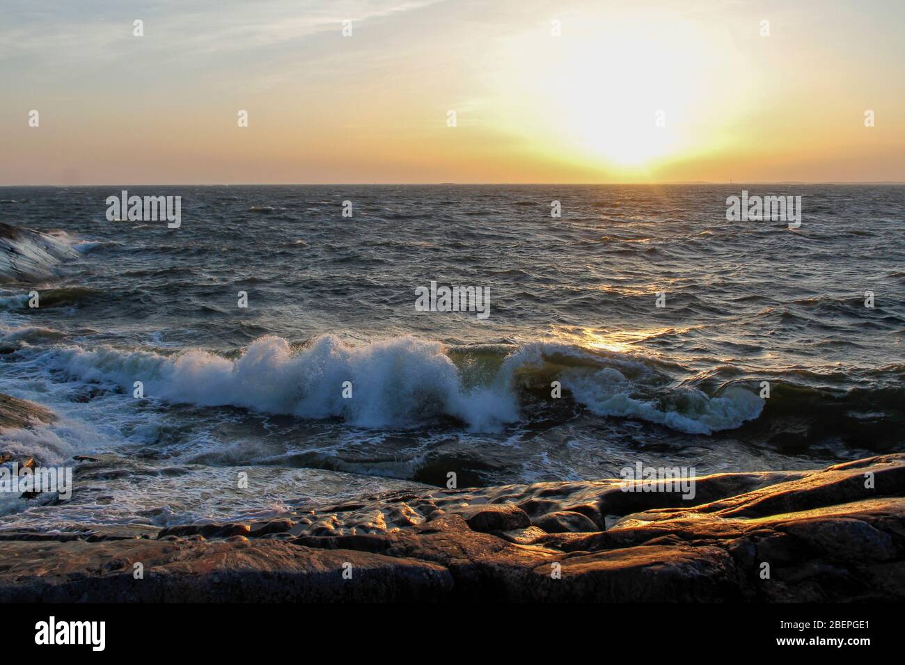 the waves hit the cliff at sunset Stock Photo - Alamy