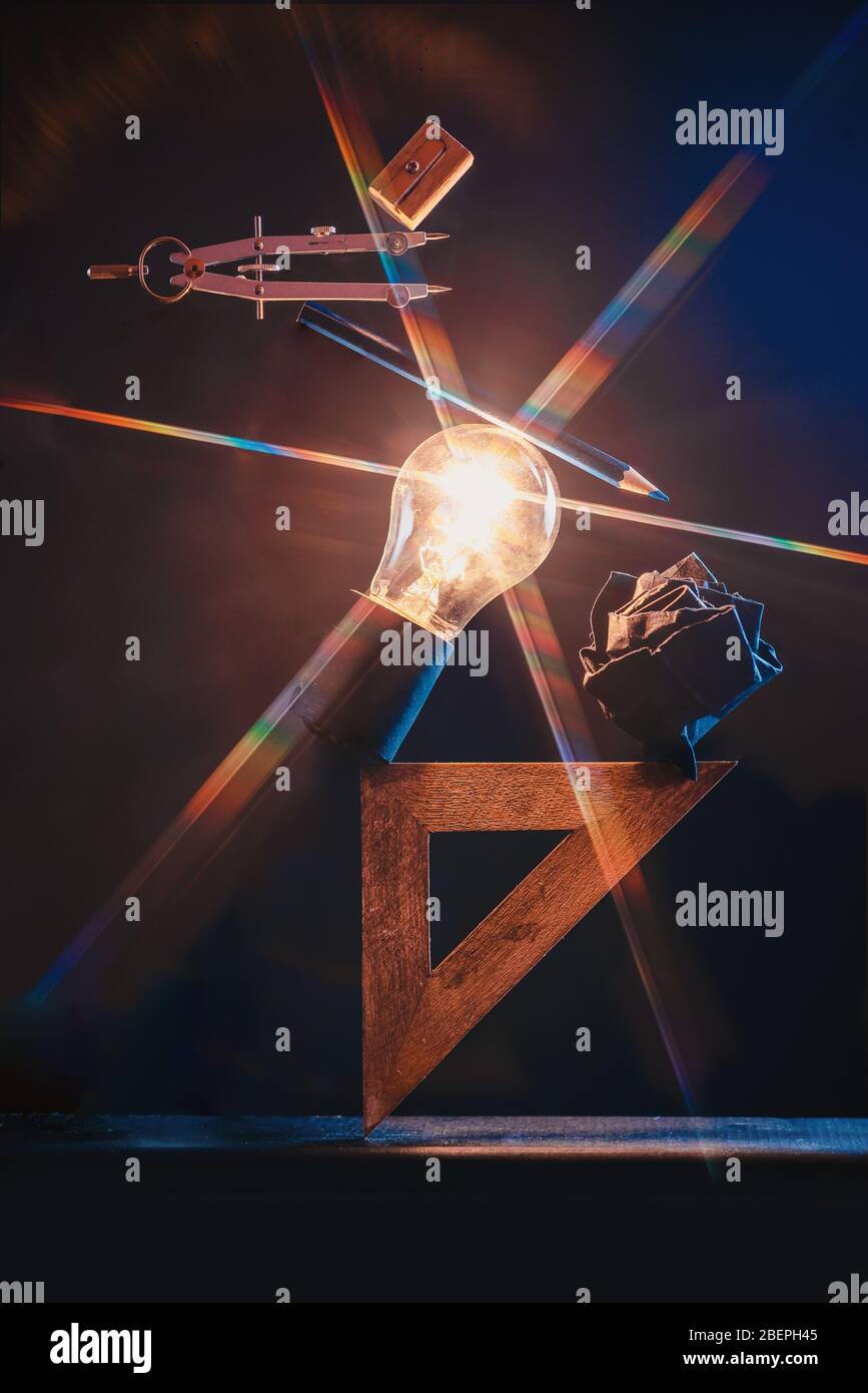Glowing lightbulb in a balancing construction of rulers, compasses and ...