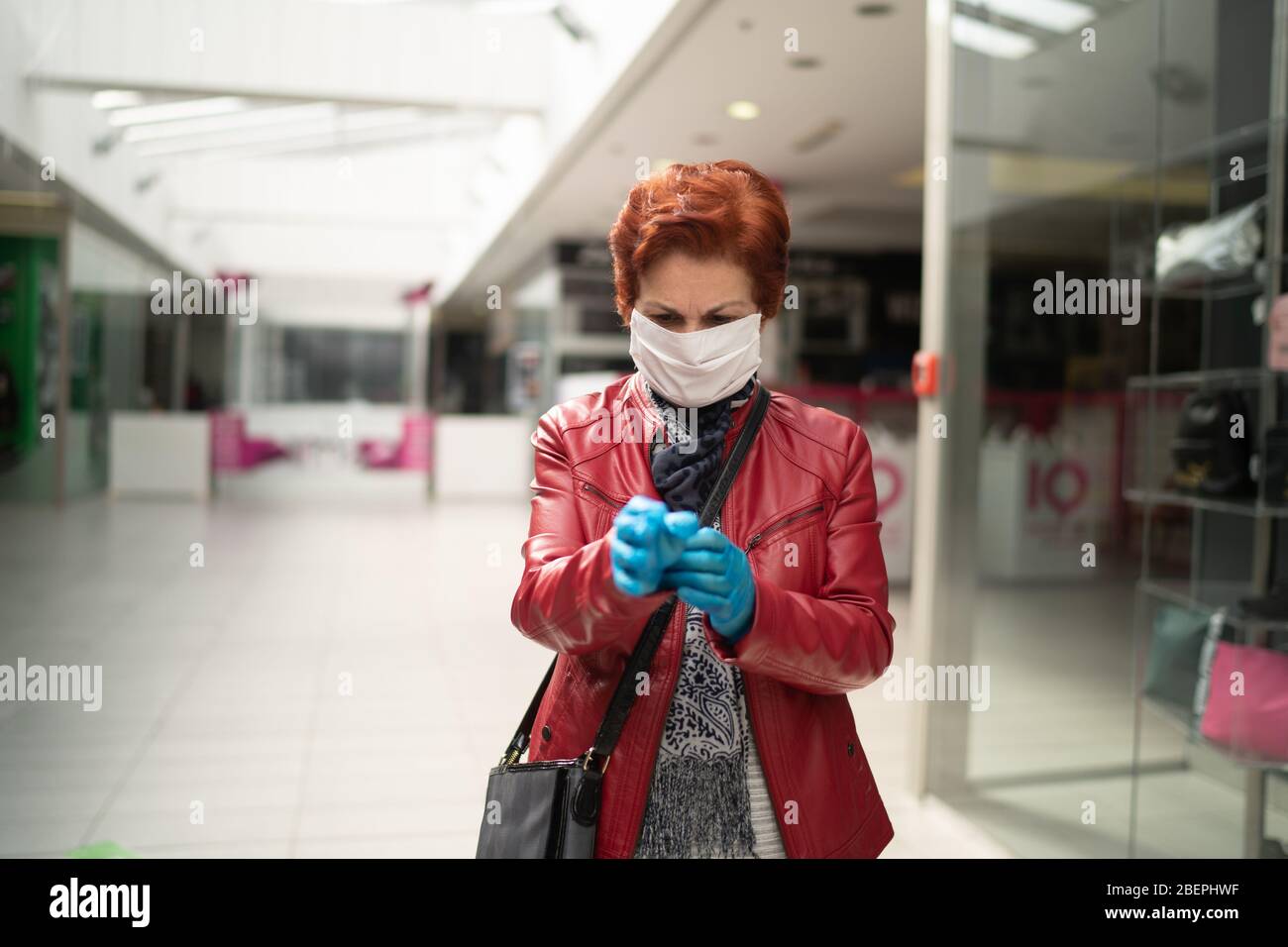 Senior elderly woman with protective cloth face mask and gloves ...