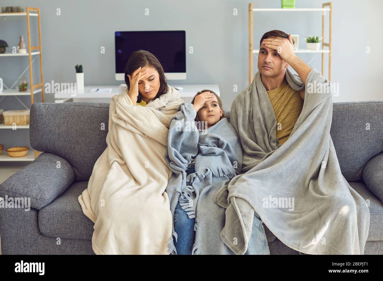 Sick family with a plaid sitting on a sofa looking at the camera with ...