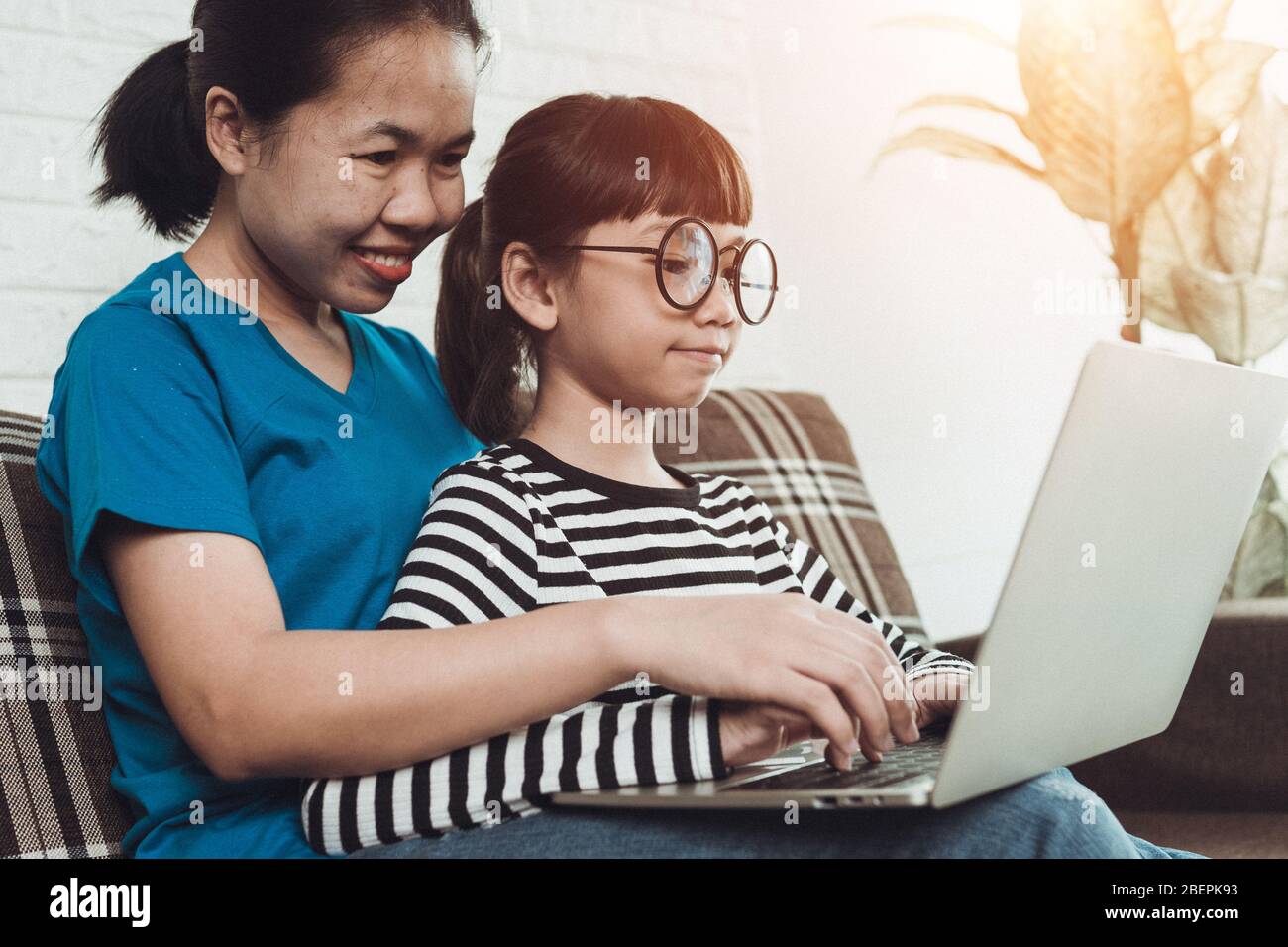 Young Asian girl kid with mom use laptop on sofa. Learning and ...