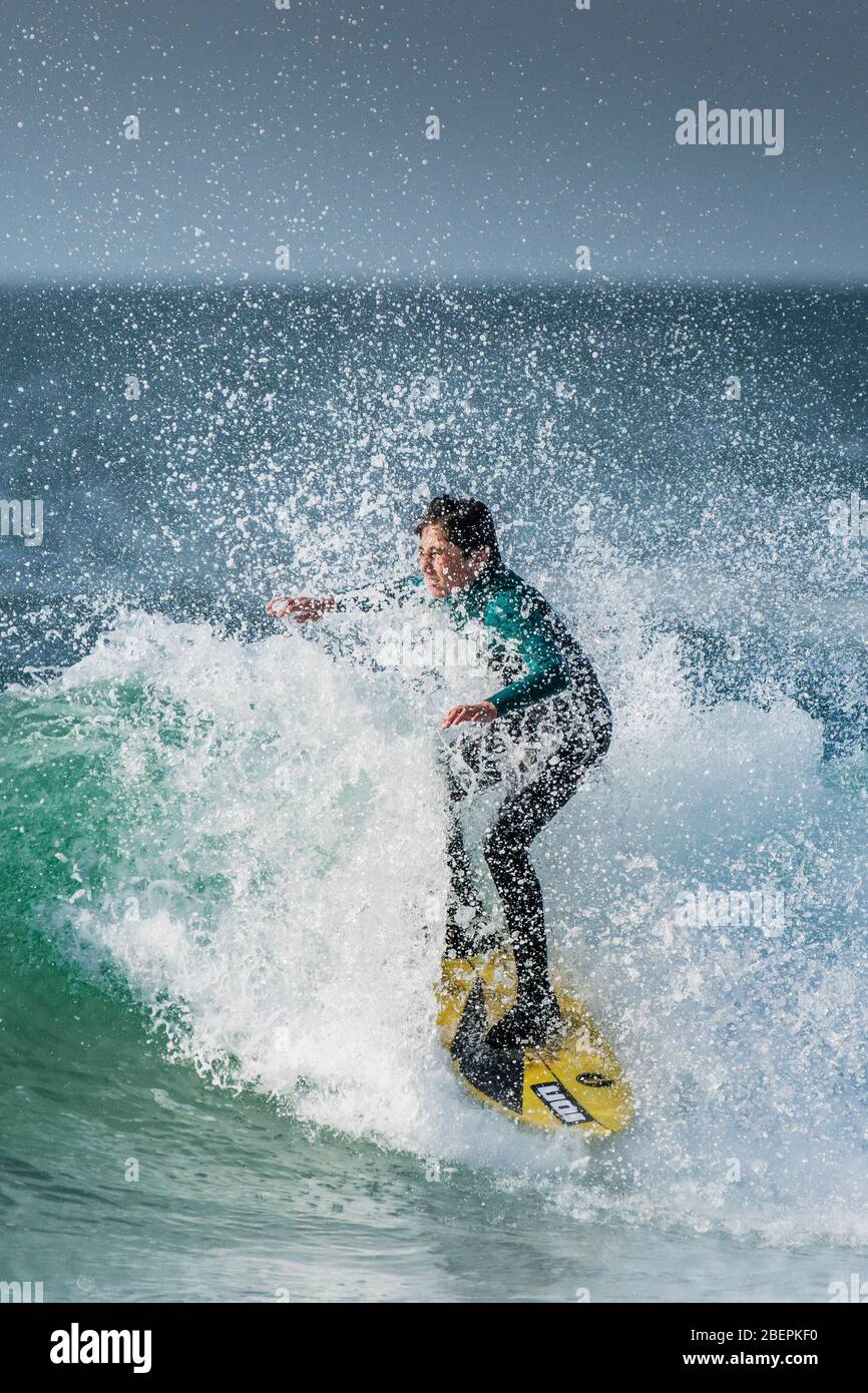 A teenage surfer in spectacular surfing action at Fistral in Newquay in ...