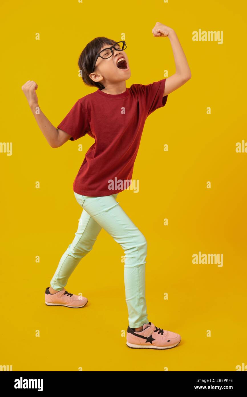 Young Asian kid in red shirt celebrate and satisfy to success on yellow ...