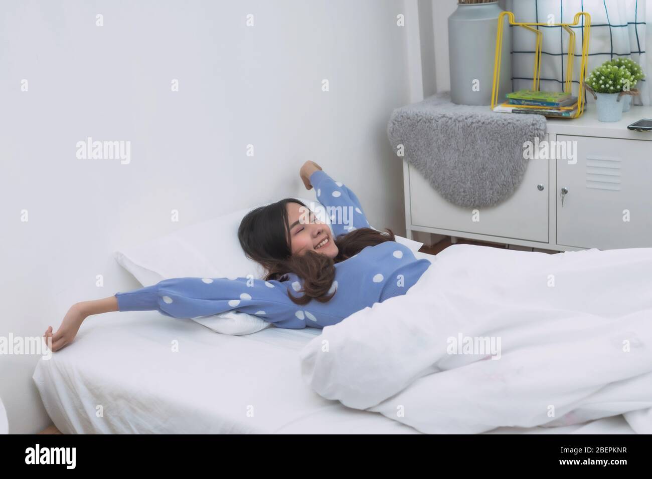 Happy cute Asia woman waking up to twist body and stretch on bed in ...