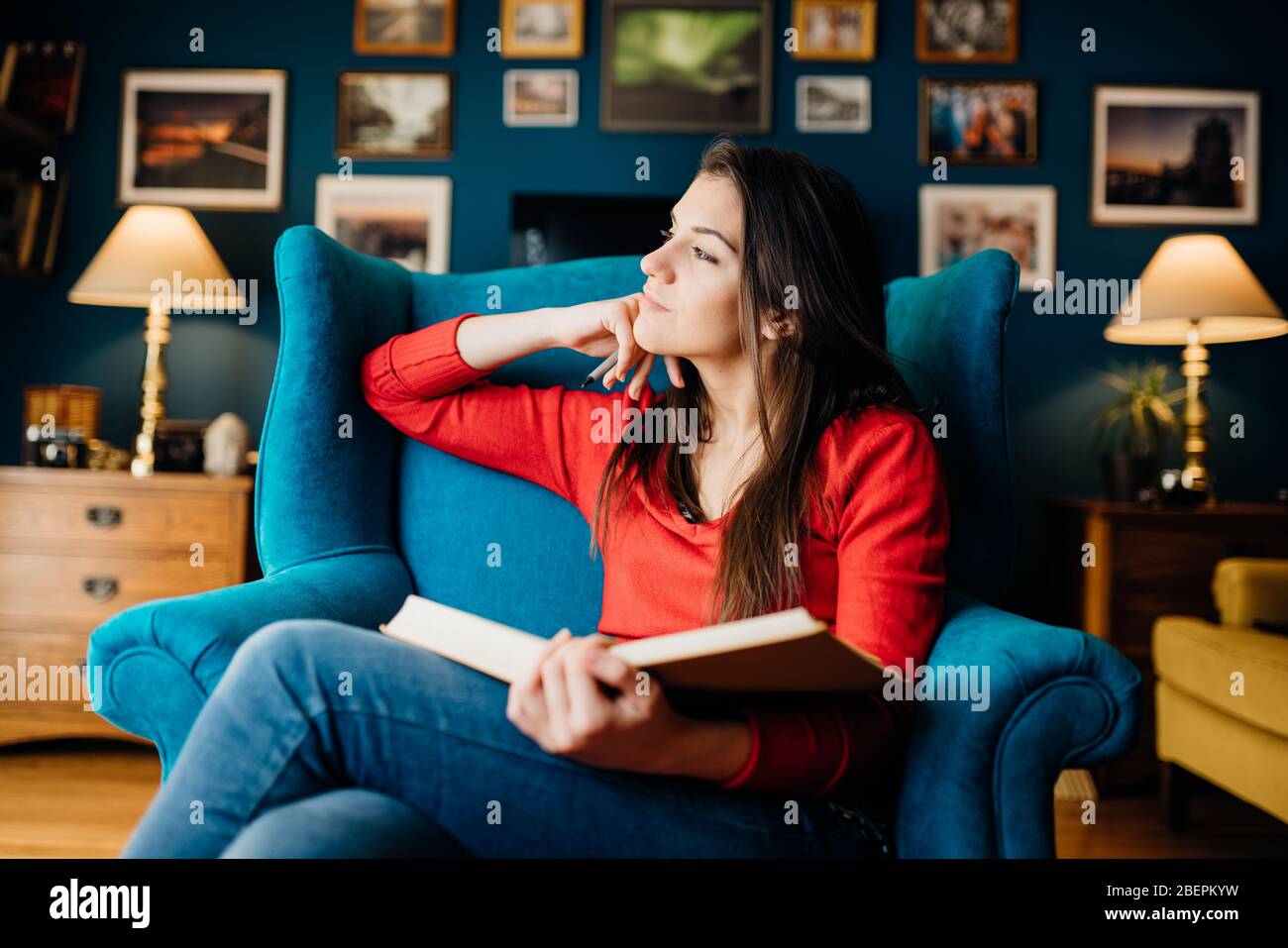 Woman thinking while reading a book at home,being distracted by her ...