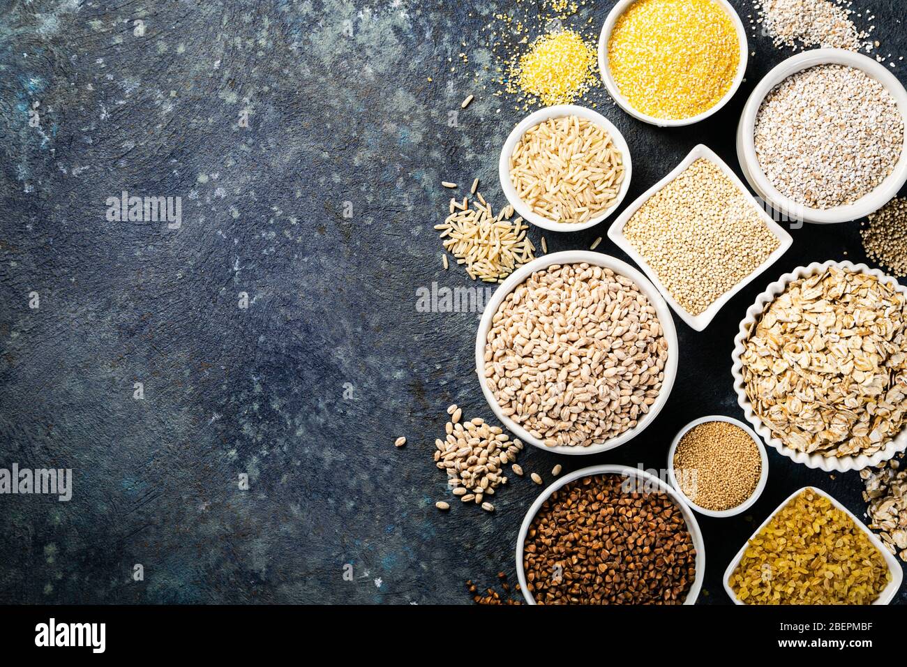 Selection of whole grains in white bowls - rice, oats, buckwheat ...