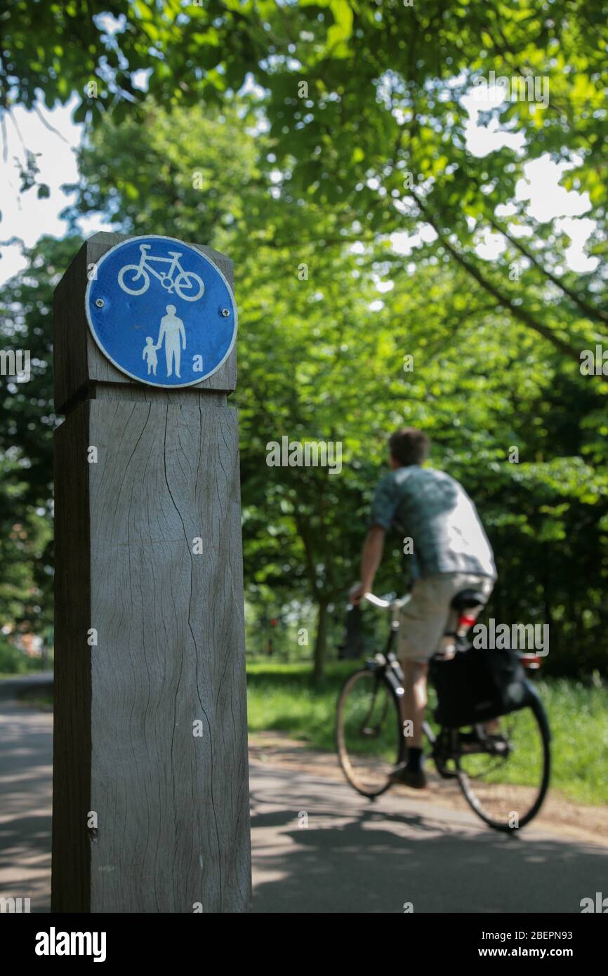 Cyclists riding past cycle path signage for both riders and pedestrians ...