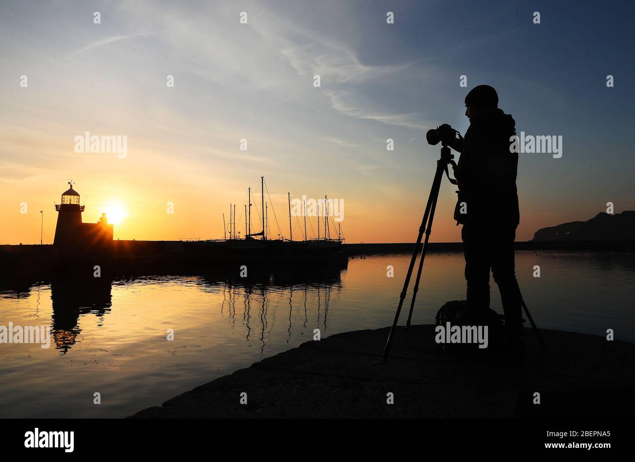 A man photographs the Howth lighthouse in Howth harbour, Dublin, as the ...