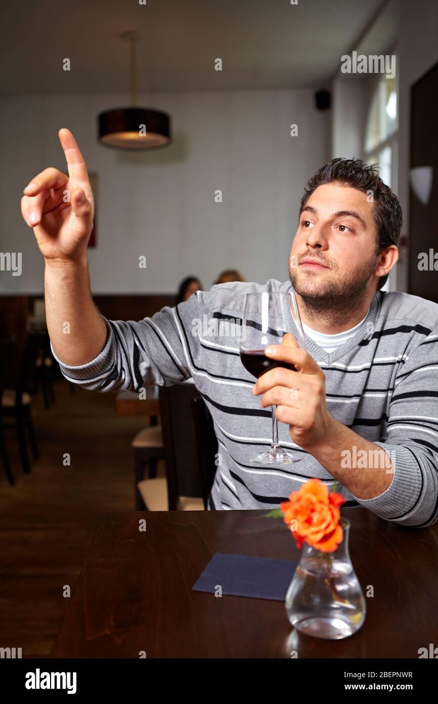 Man in restaurant with wine glass calls the waiter Stock Photo - Alamy