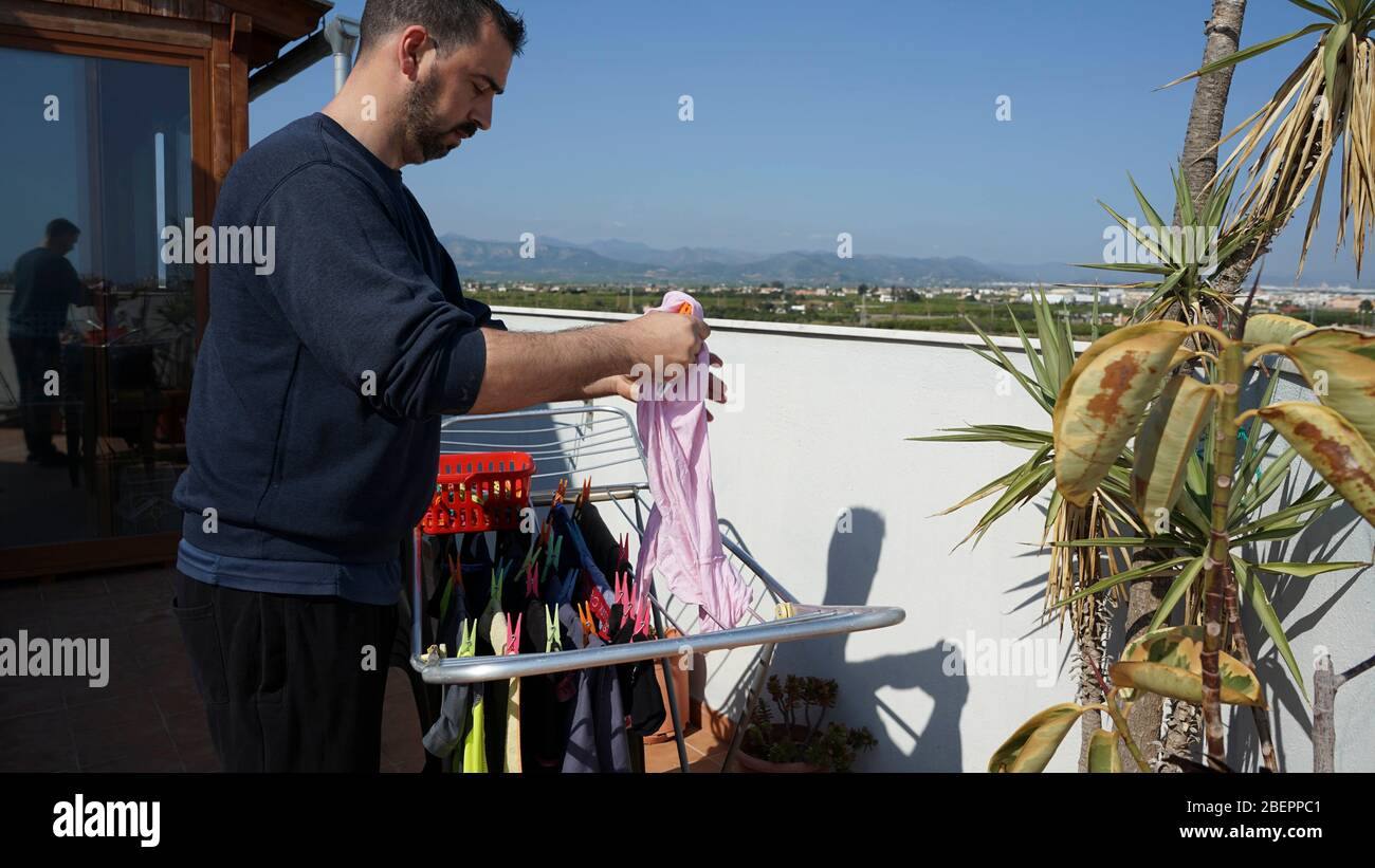 Man hanging clothes on the terrace of his house Stock Photo - Alamy