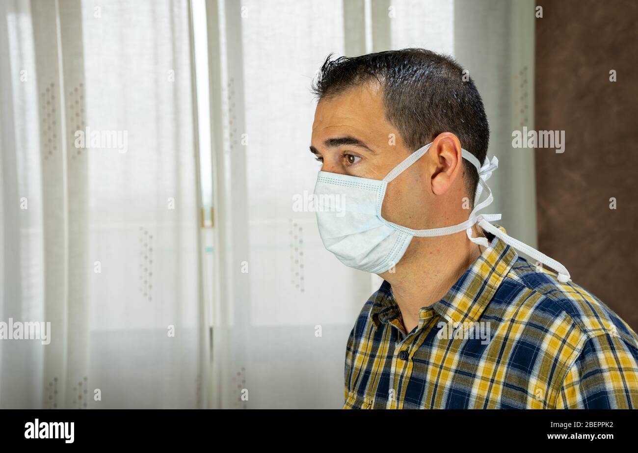 Man posing with mask in the living room of his house protecting himself ...