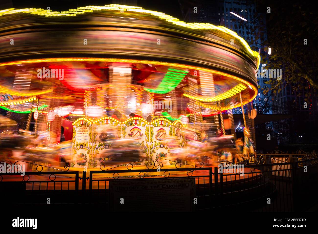 A vintage carousel spinning at night leaving vibrant and colorful light ...