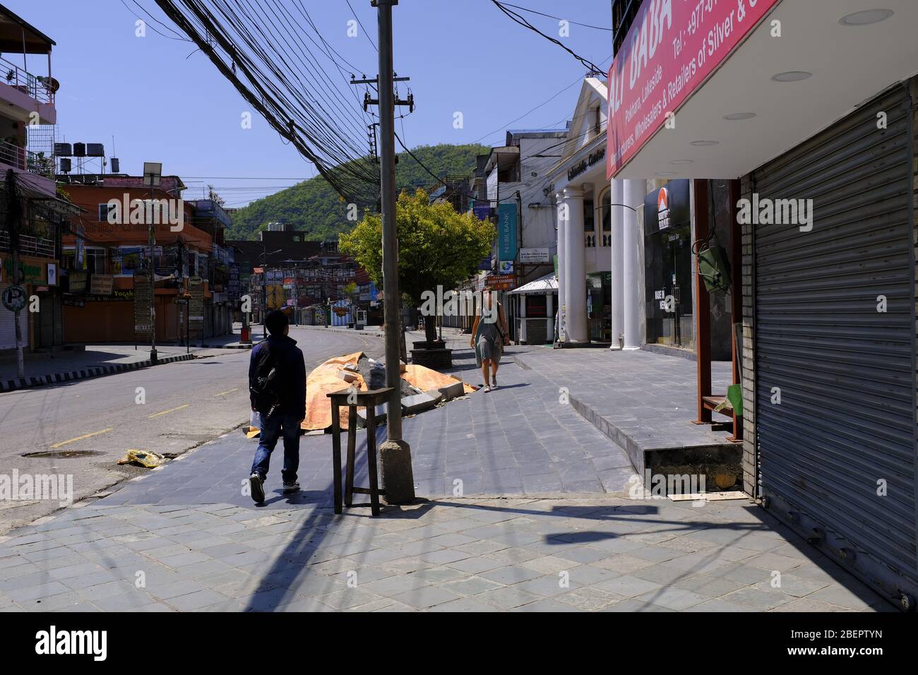 A man and a tourist walking in an empty street of Pokhara city during ...