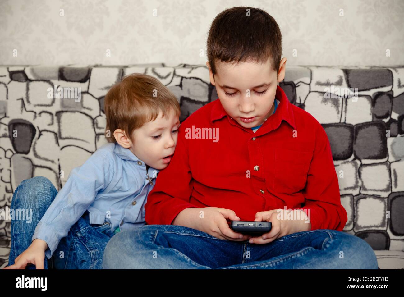 Cute kids playing game console at home. Boys play in tablet together ...