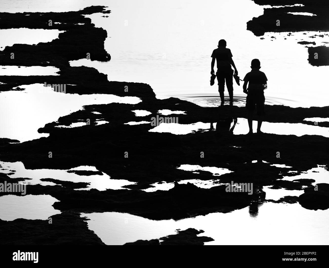 Silhouette of two children exploring rock pools in Akko, Israel Stock ...